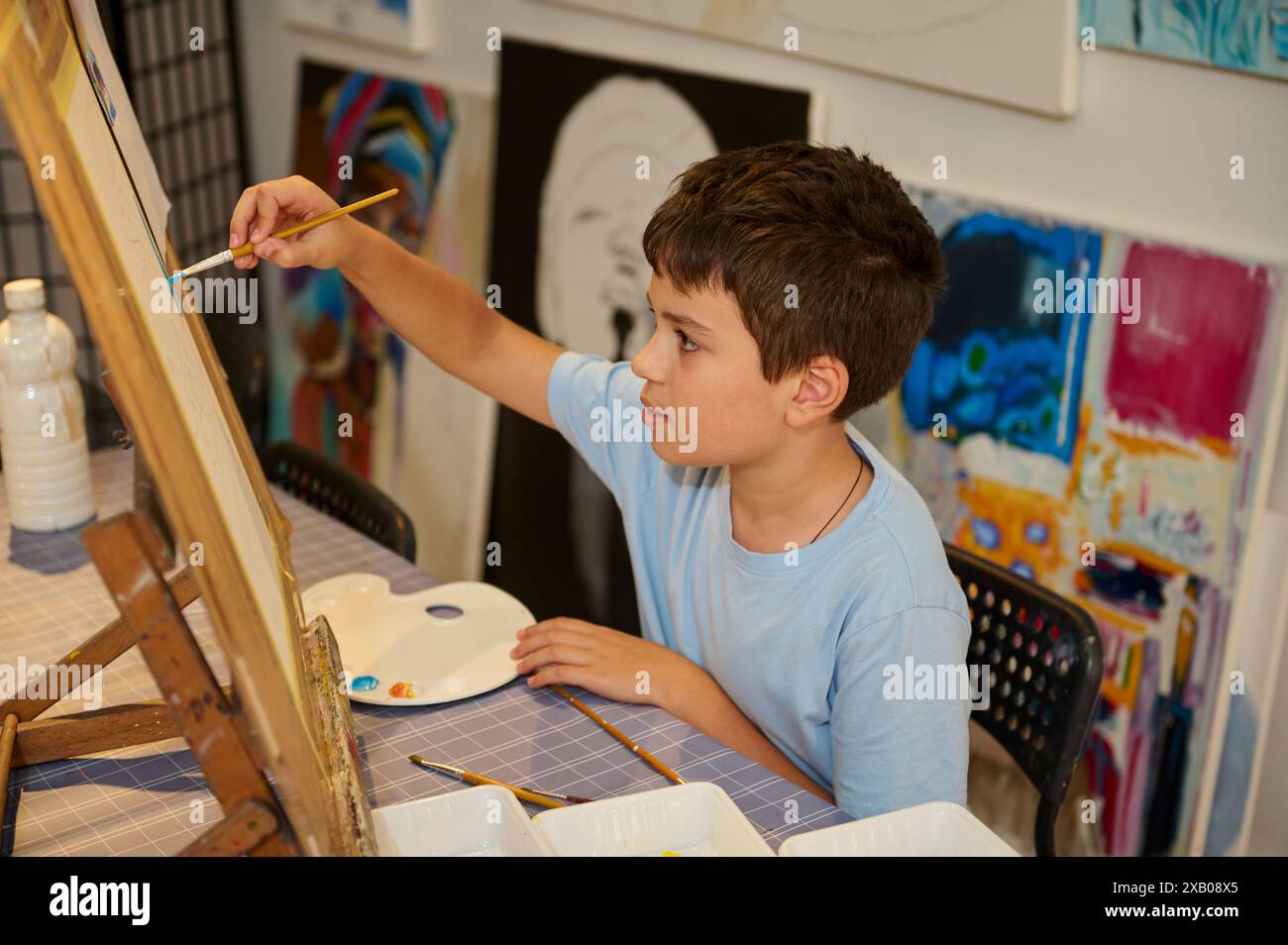 Young boy painting on canvas in art class workshop with vibrant ...