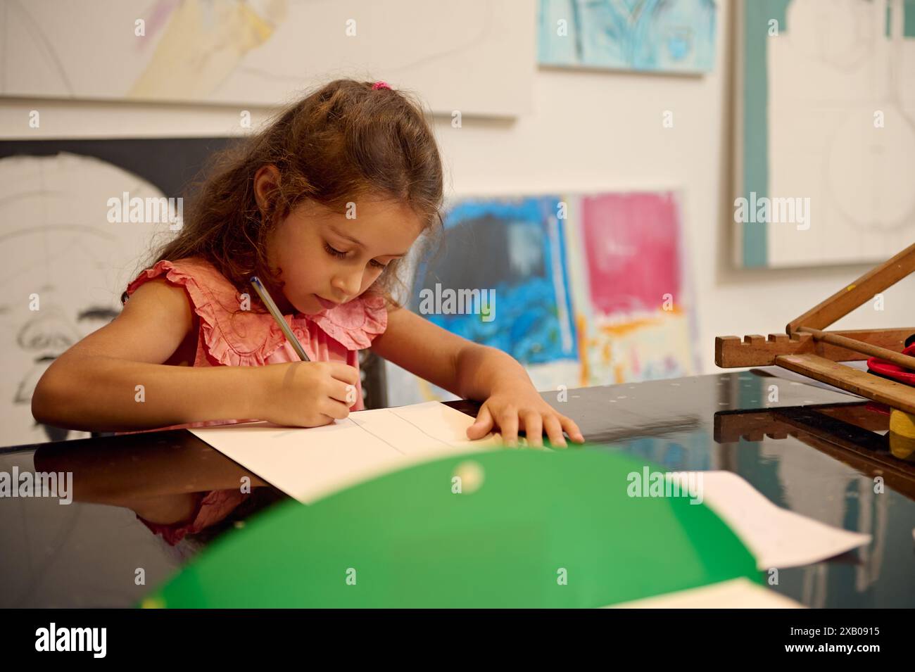Young girl drawing in art class with colorful paintings around Stock ...