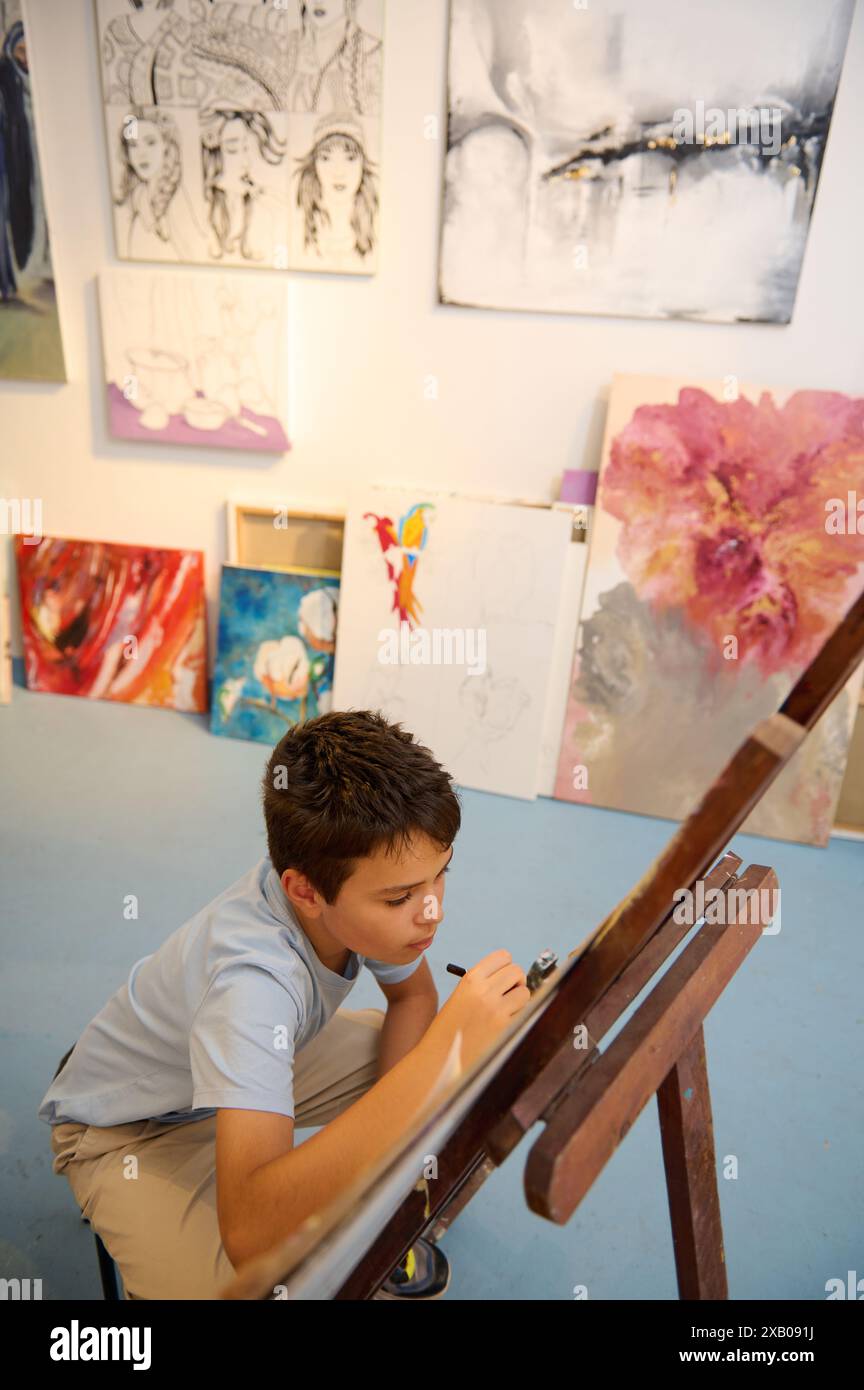 Young boy drawing in art class surrounded by inspirational artworks ...