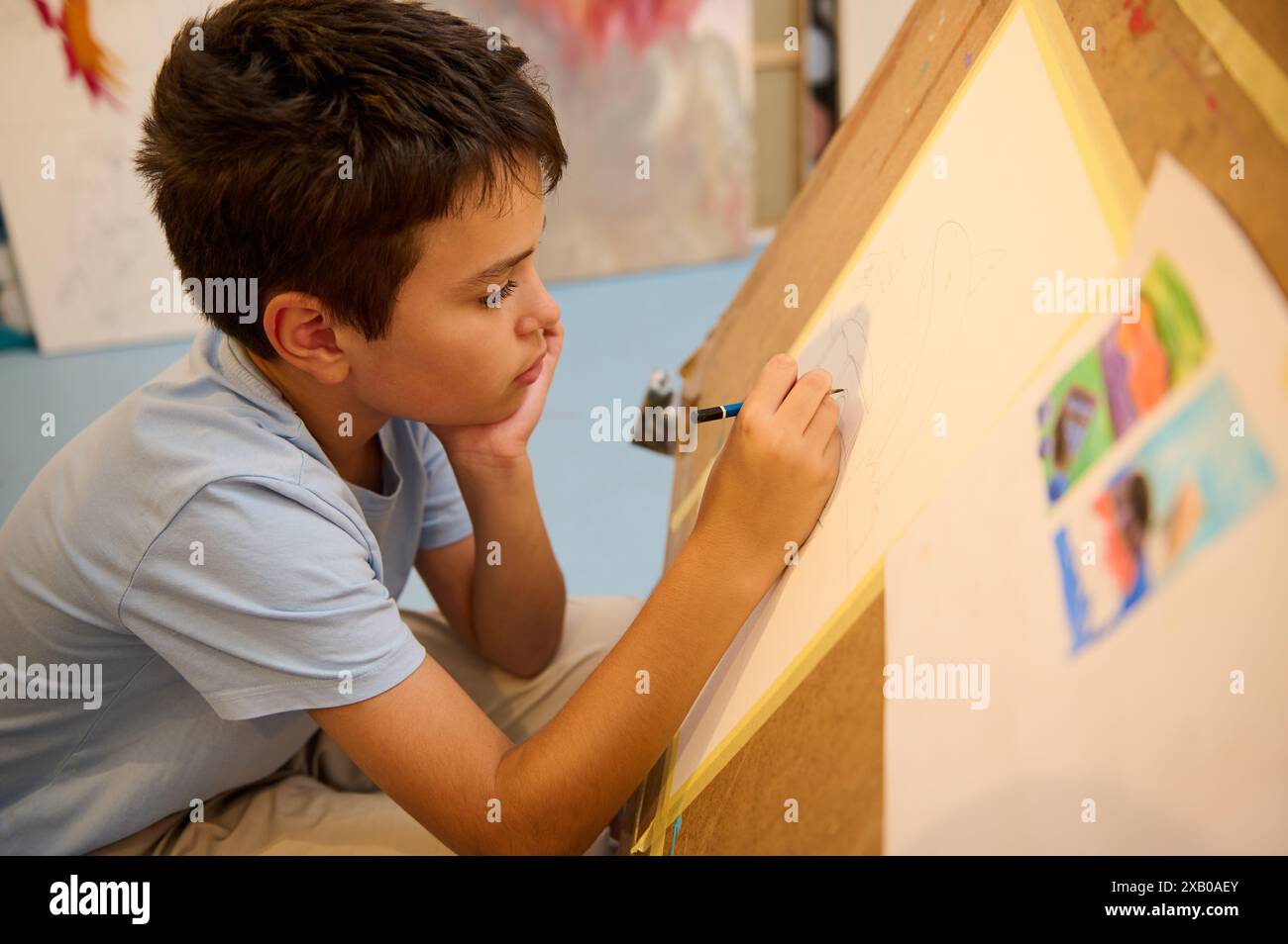 Boy concentrating on drawing during art class workshop with colorful ...