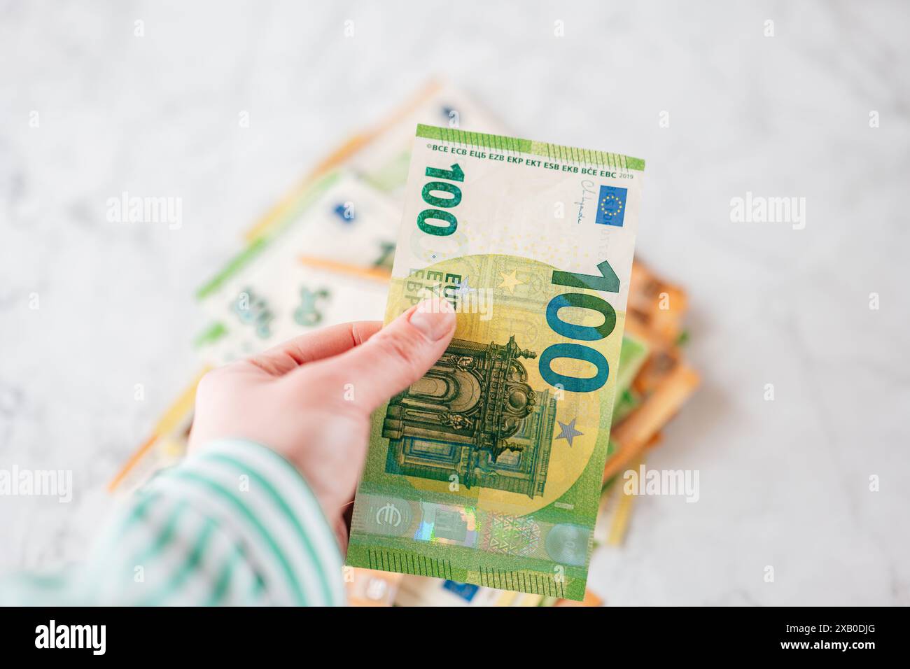 one hundred euro banknote in hand. counting Euro bills on a marble ...