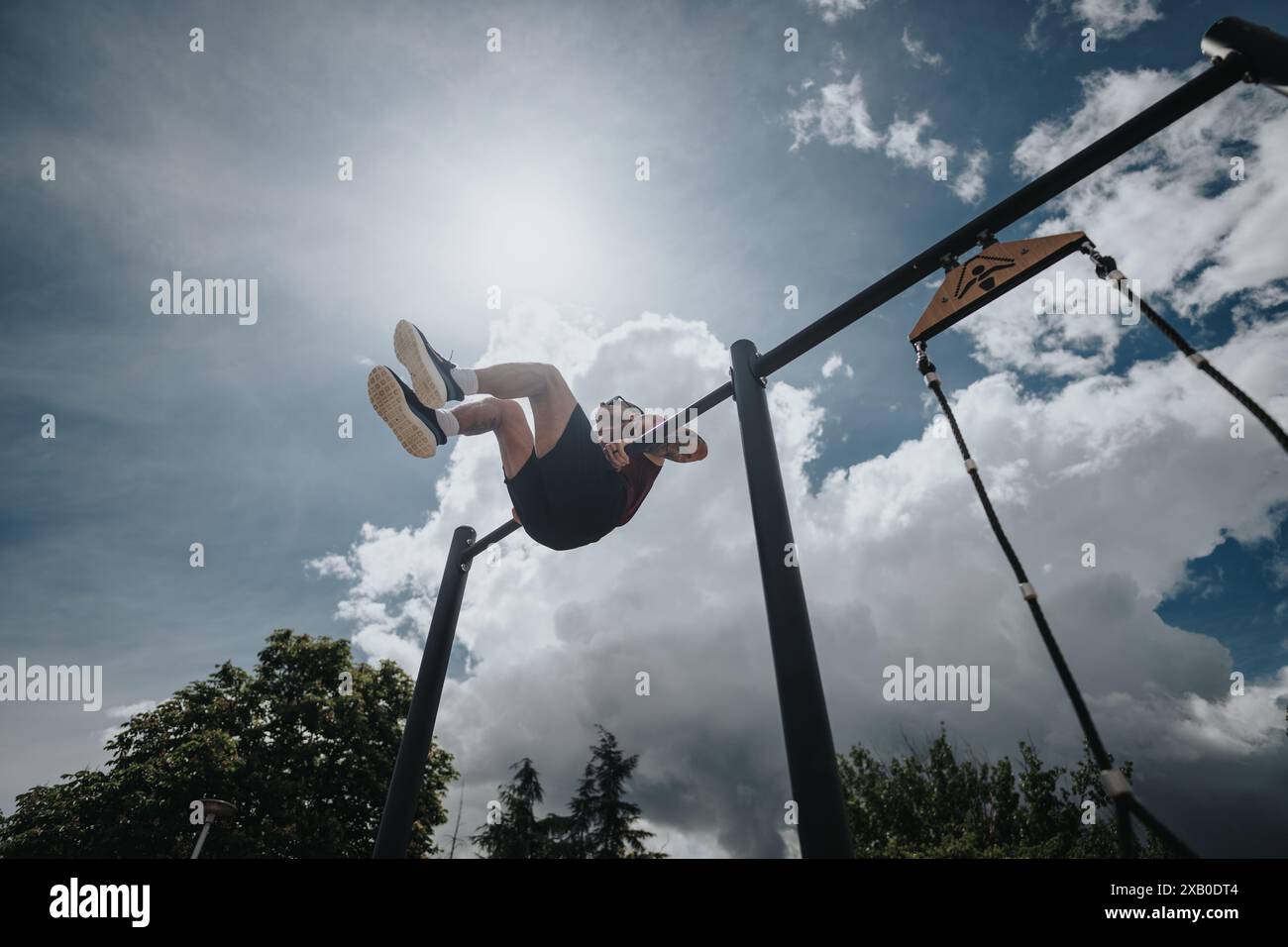 Athletic man performing calisthenics in a sunny urban park, showcasing ...