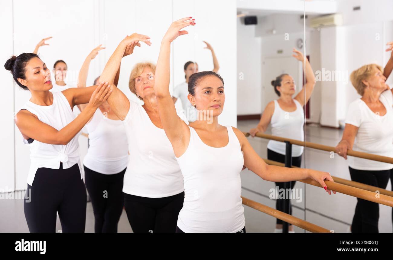 Dancing women stand in a ballet stance, where the choreographer helps ...