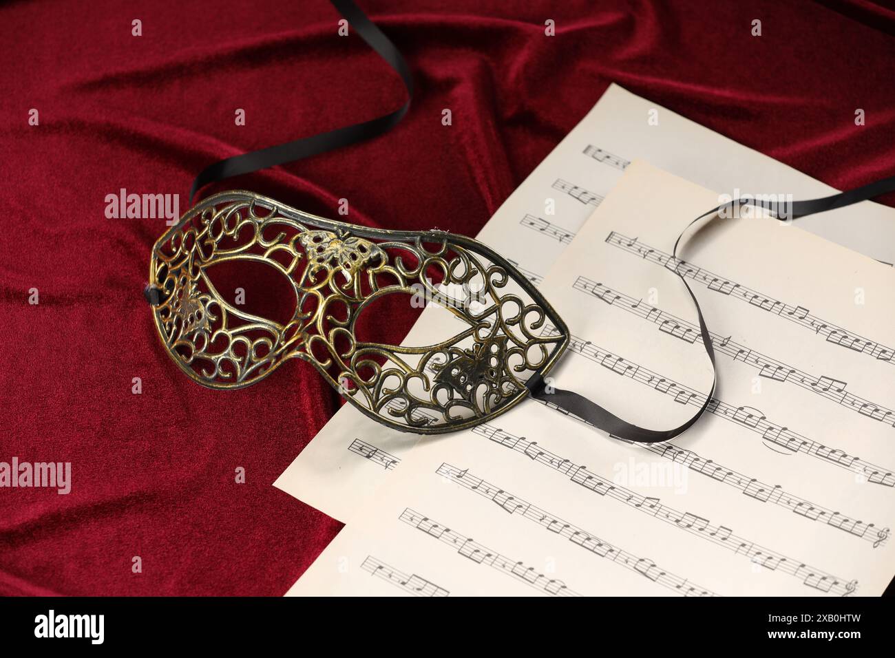 Elegant face mask and music sheets on red fabric. Theatrical ...
