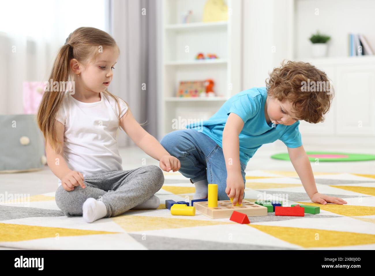 Cute little children playing with set of wooden geometric figures on ...