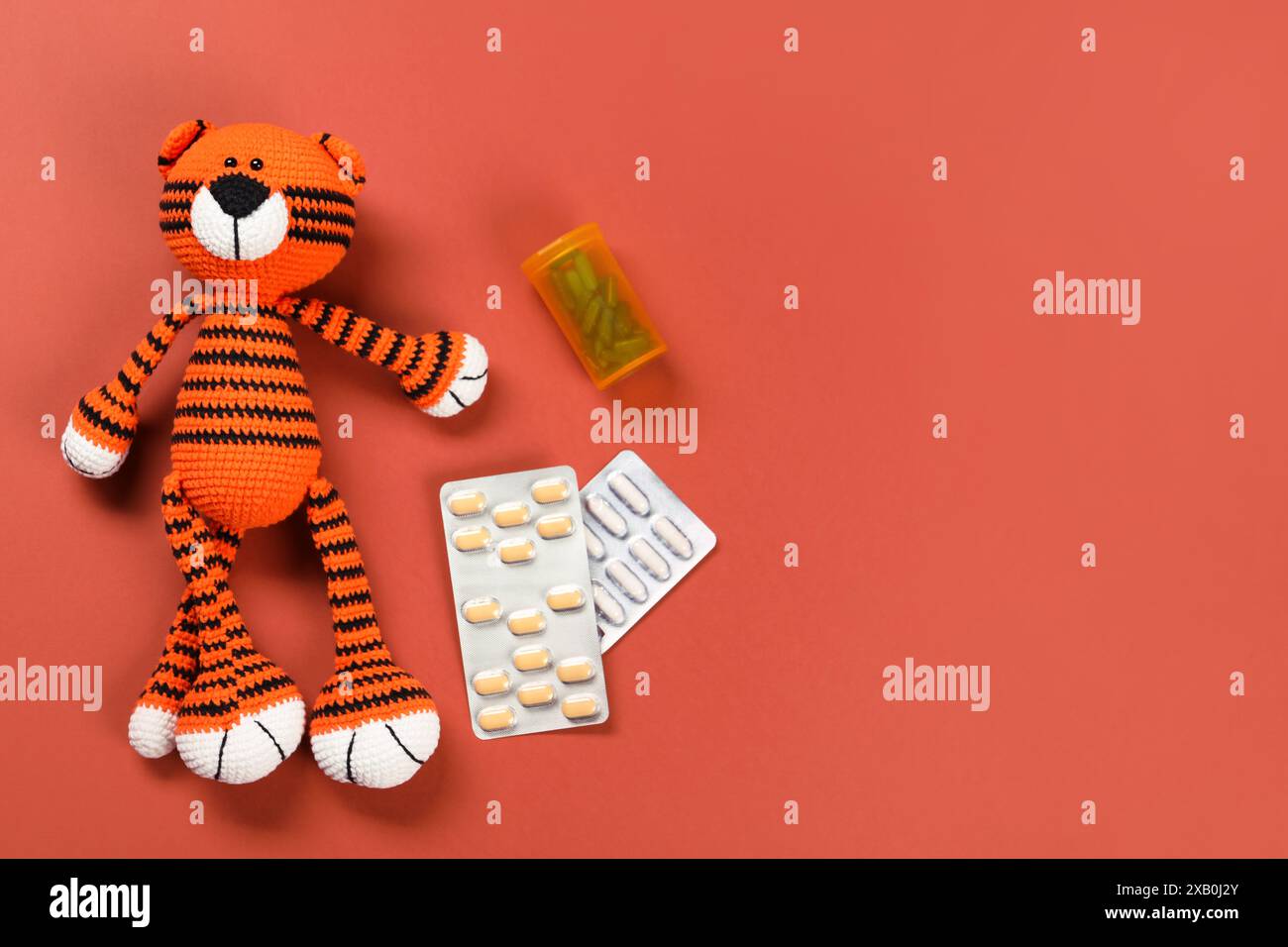 Toy tiger and pills on orange background, flat lay. Space for text ...