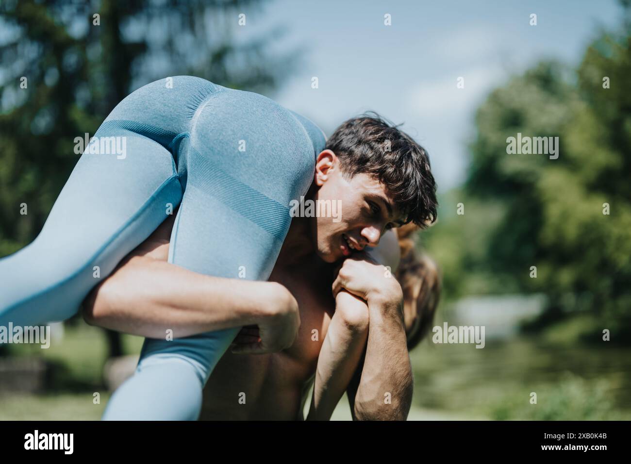 Strong man exercising outdoors with weight and carrying a friend on his ...