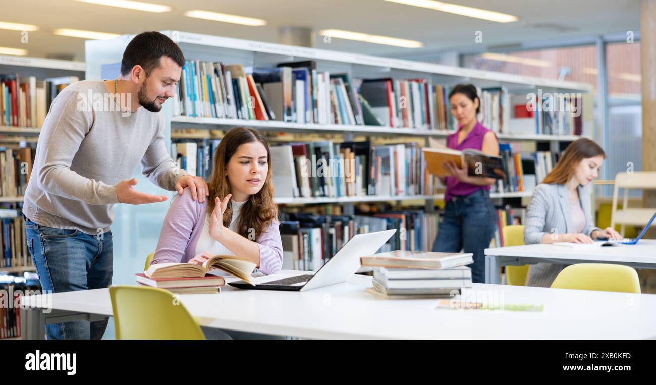 Woman gesturing to stop guy flirting with her in library Stock Photo ...