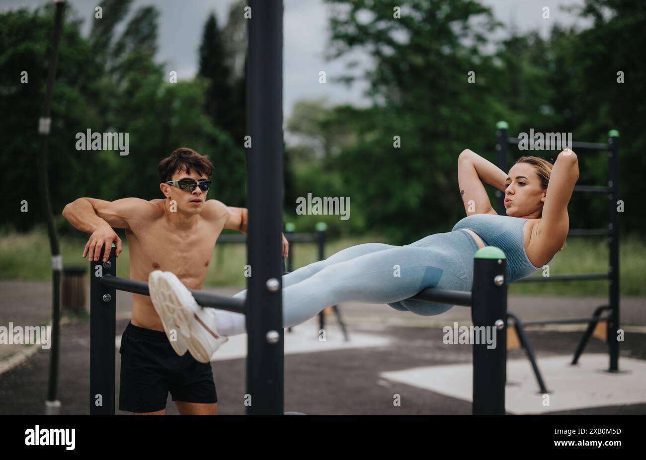 Outdoor calisthenics workout with two athletes exercising on bars in a ...