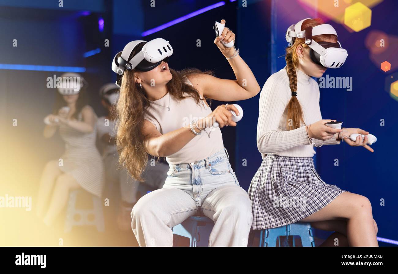 Female friends competing in two-on-two virtual reality game Stock Photo ...
