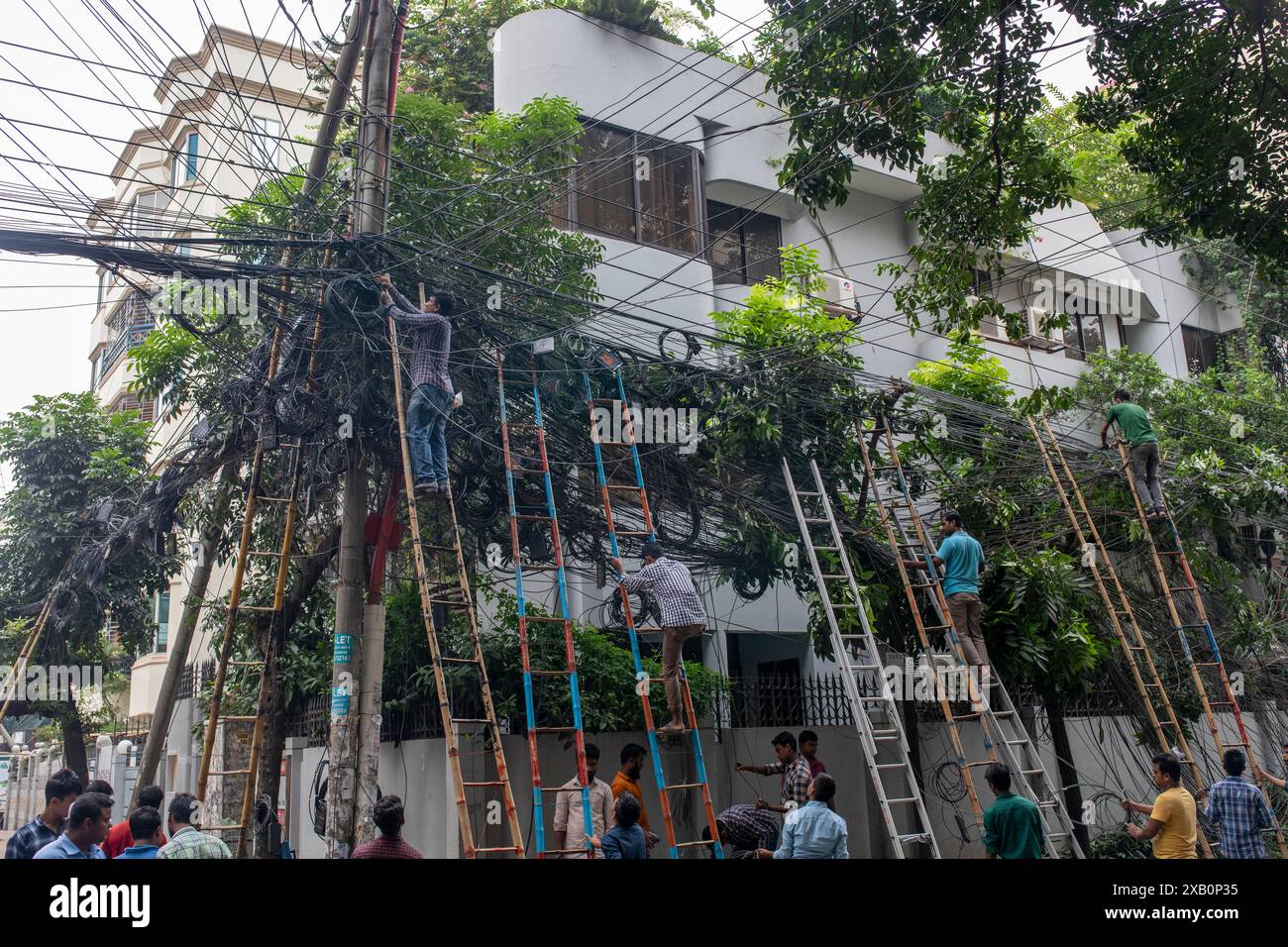 Workers repairing overhead internet cables damaged by a storm in Dhaka ...