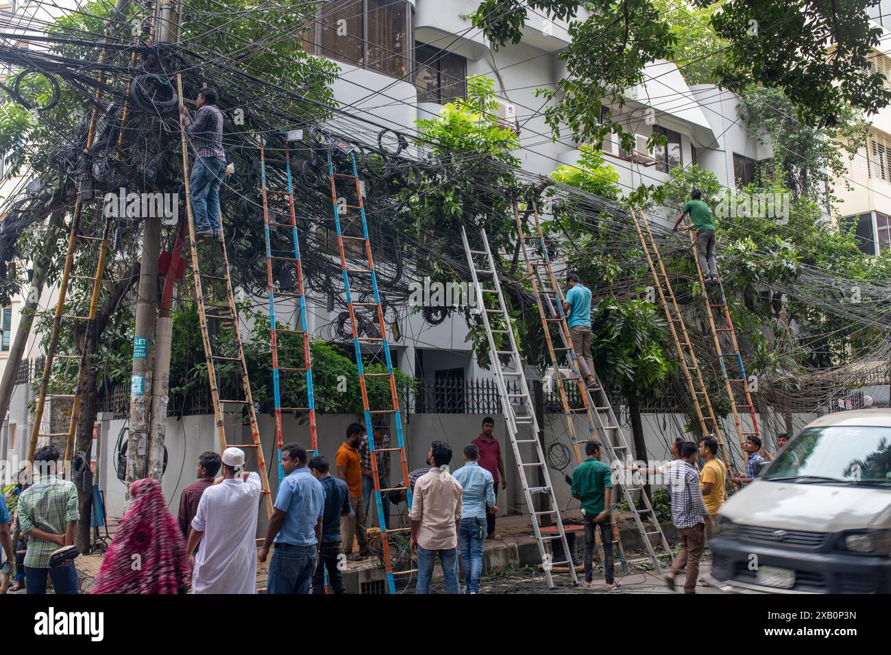 Workers repairing overhead internet cables damaged by a storm in Dhaka ...