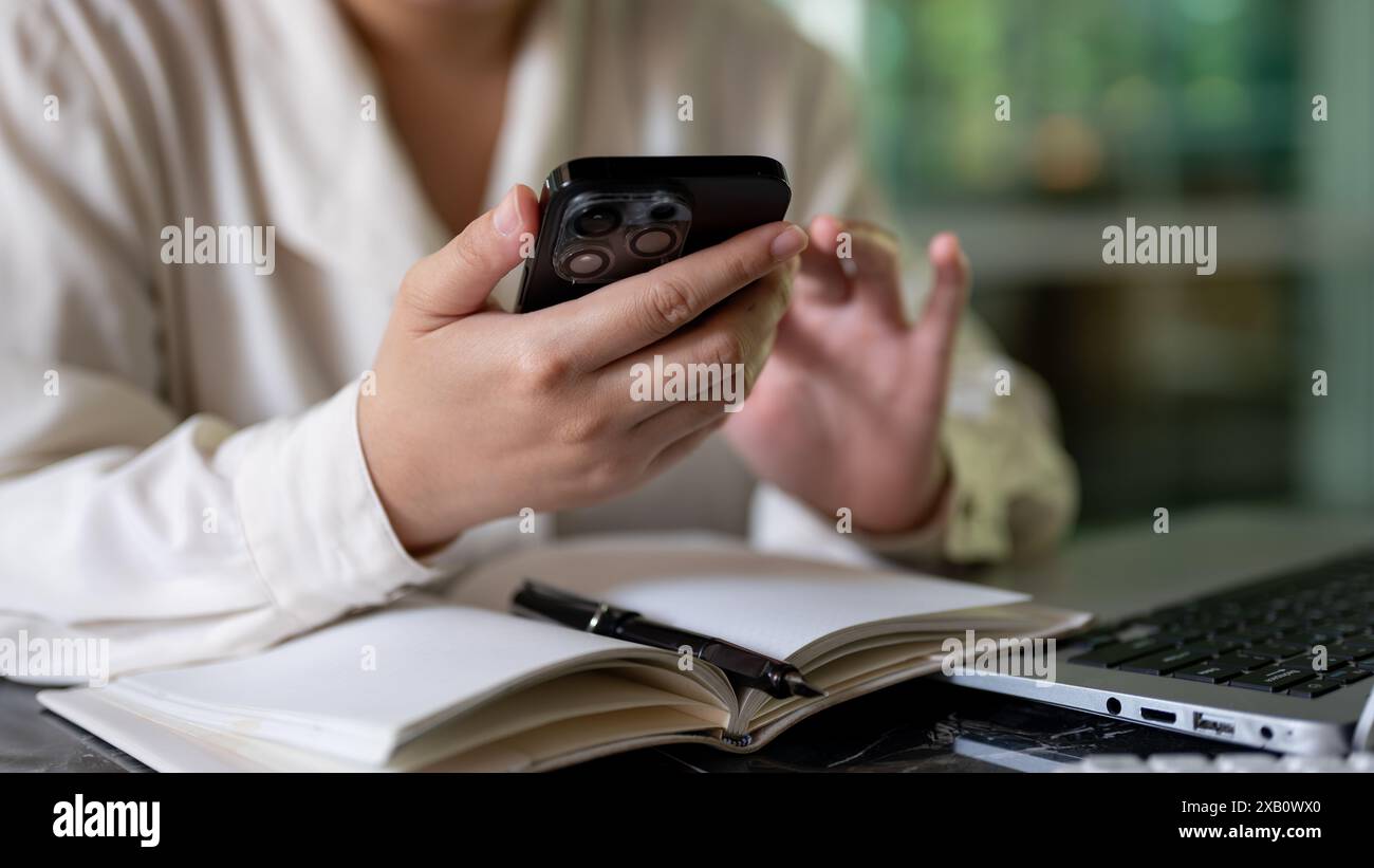A cropped image of an Asian businesswoman using her smartphone at her ...
