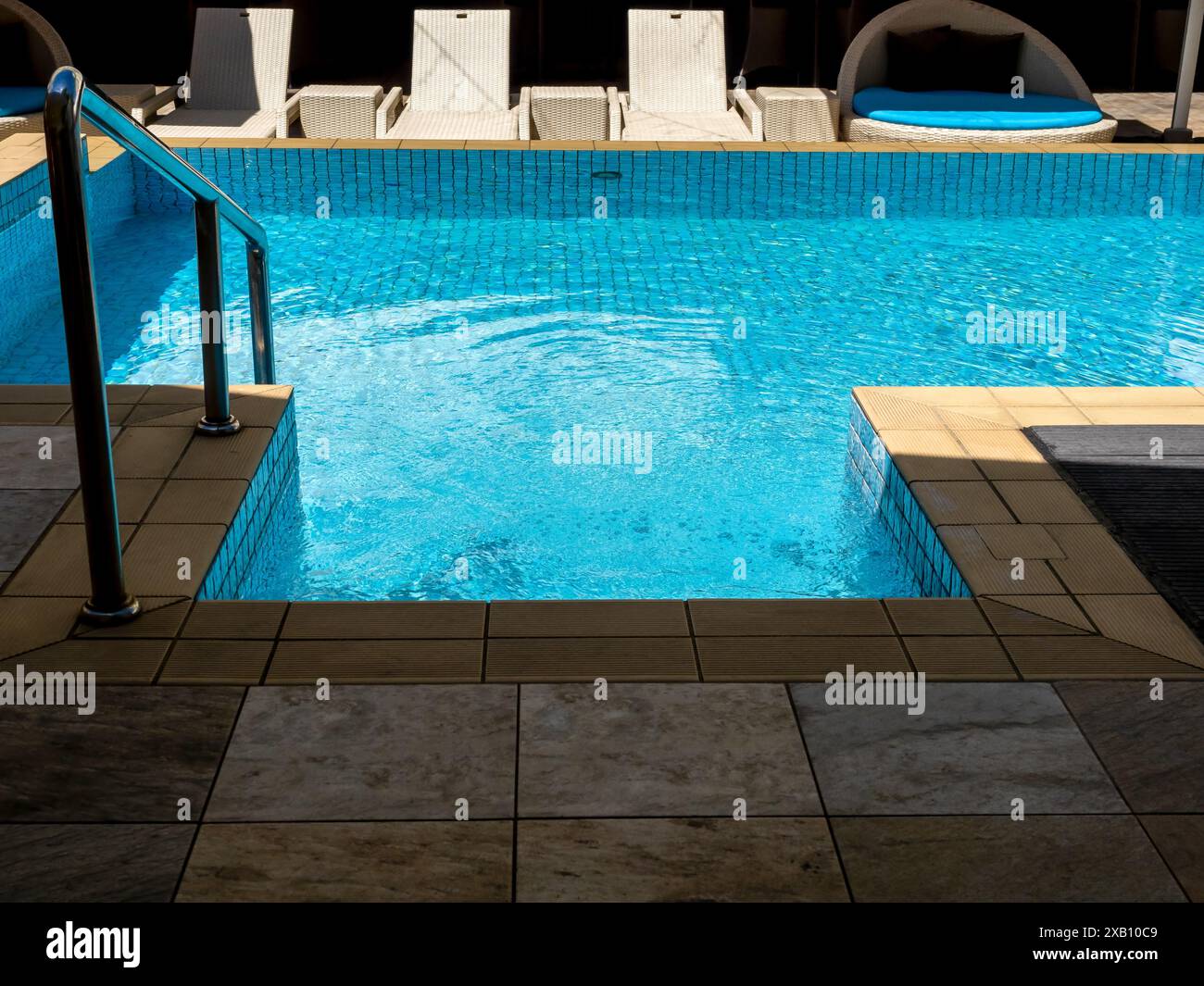 Clear water surface background on swimming pool steps with chrome grab ...