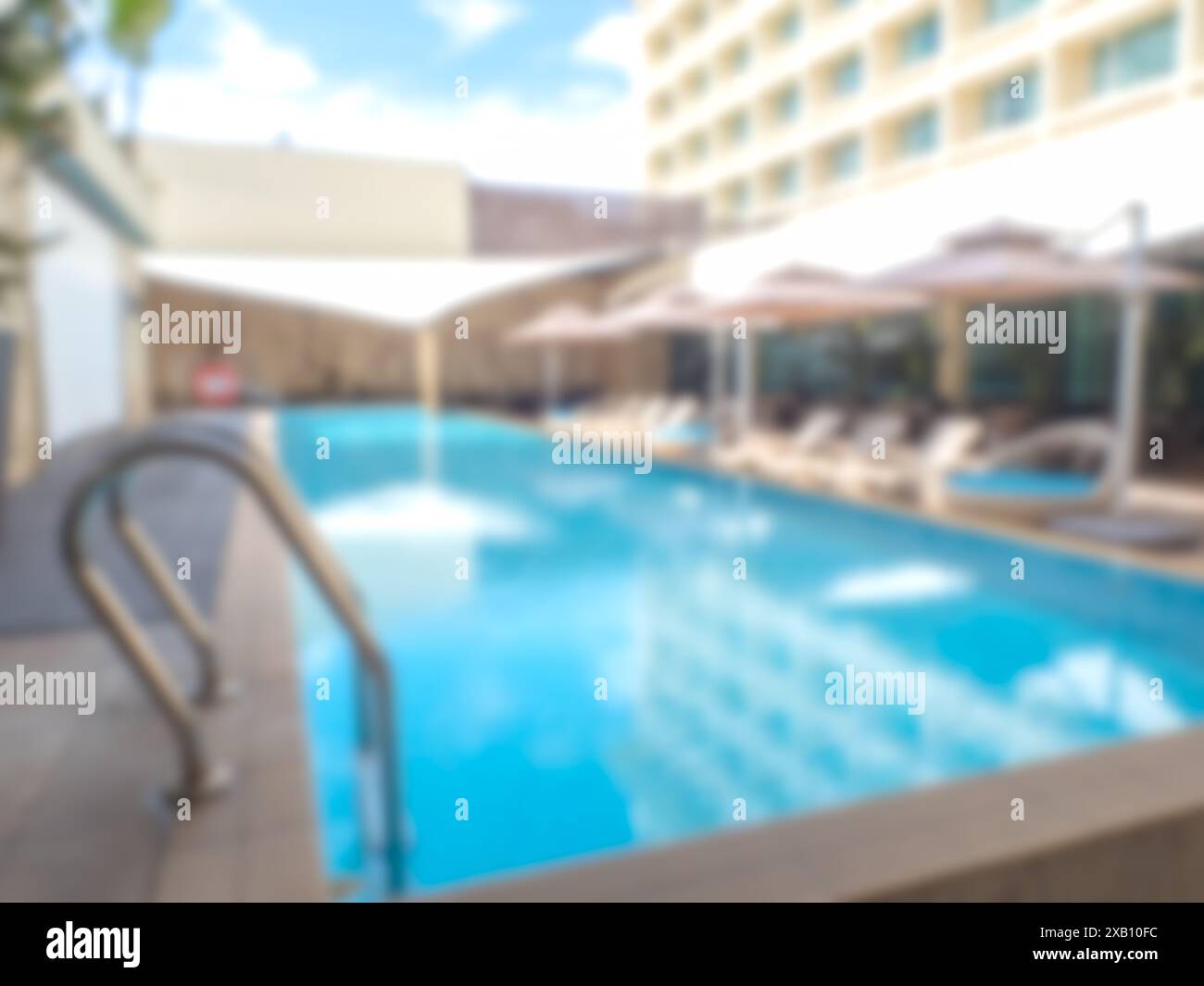 Abstract blur outdoor swimming pool with grab bar stair and sunbeds ...