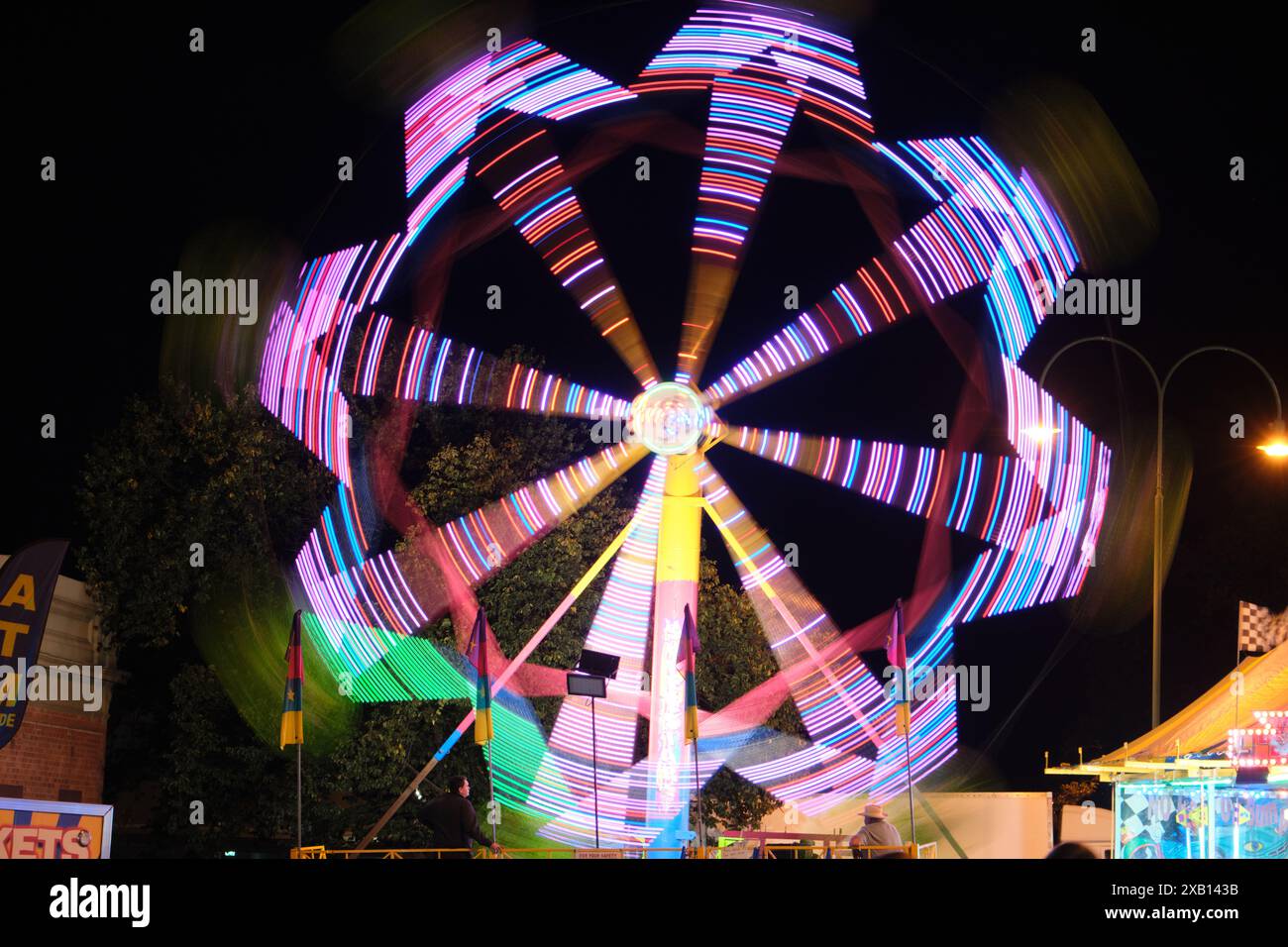 Colorful lights on spinning Ferris wheel at night at a town fair Stock ...