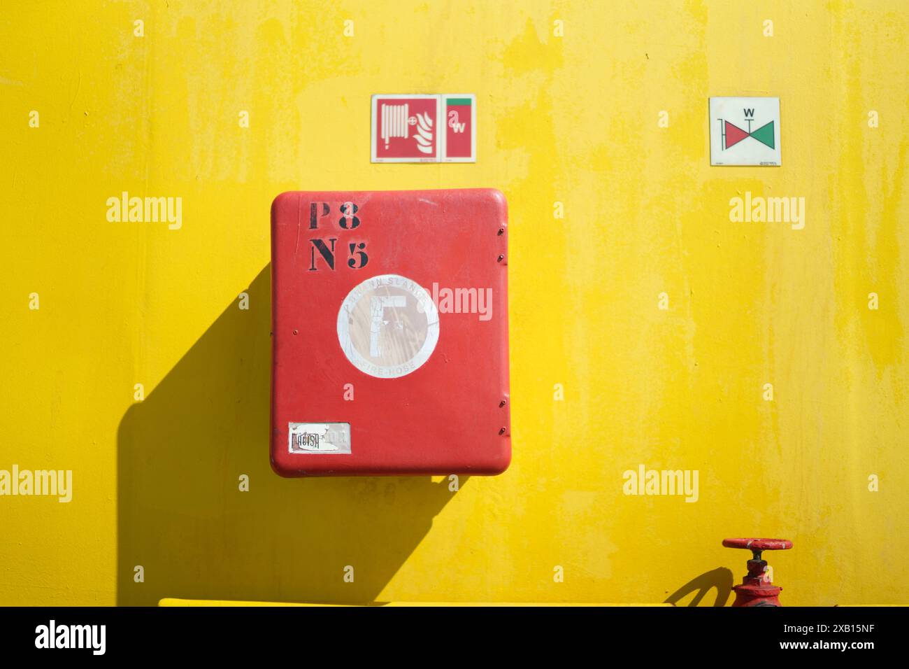 Bright red fire hose box on a yellow wall of a cross channel ferry ...