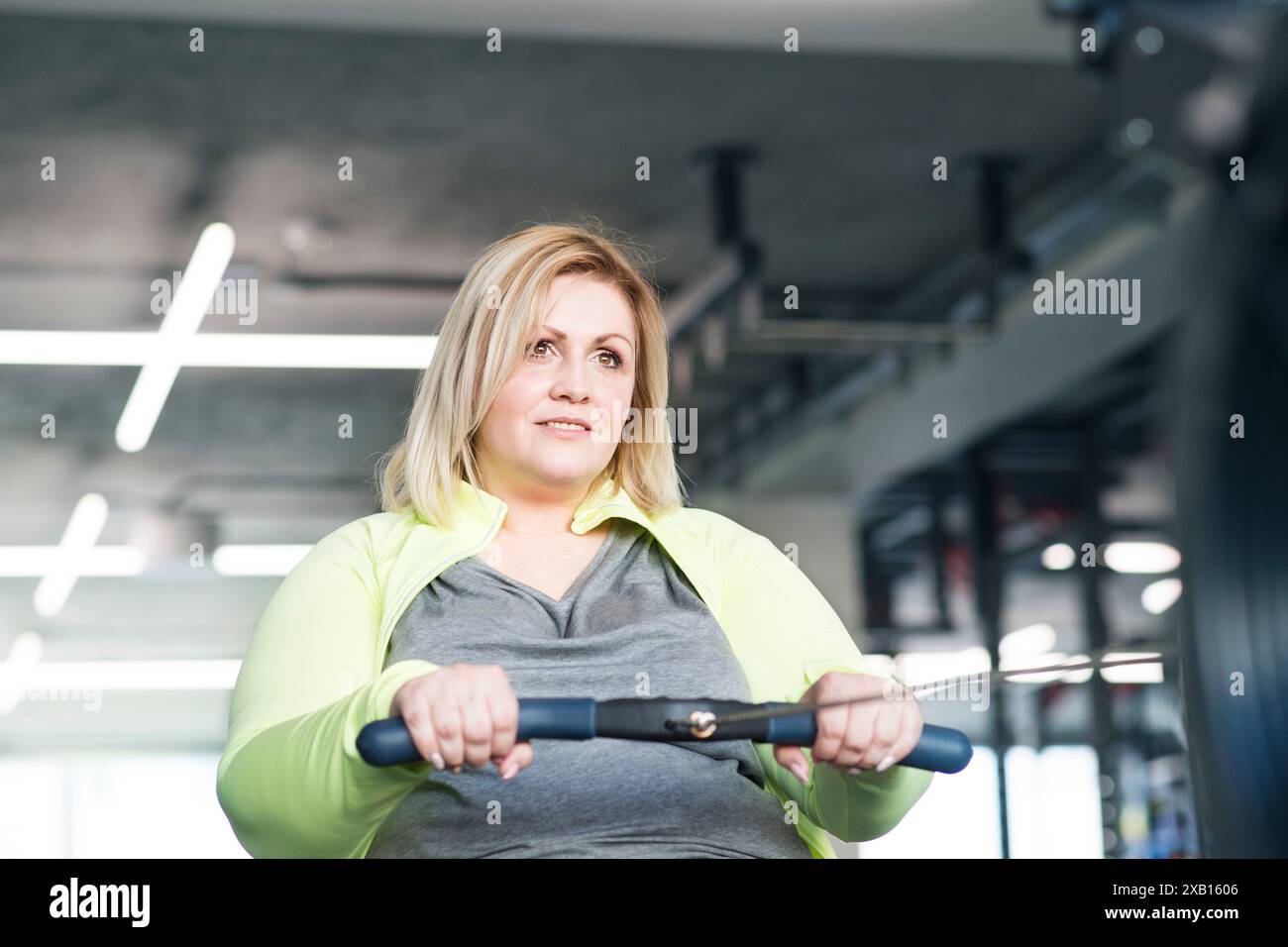 Overweight woman exercising on rowing machine. Routine workout for ...