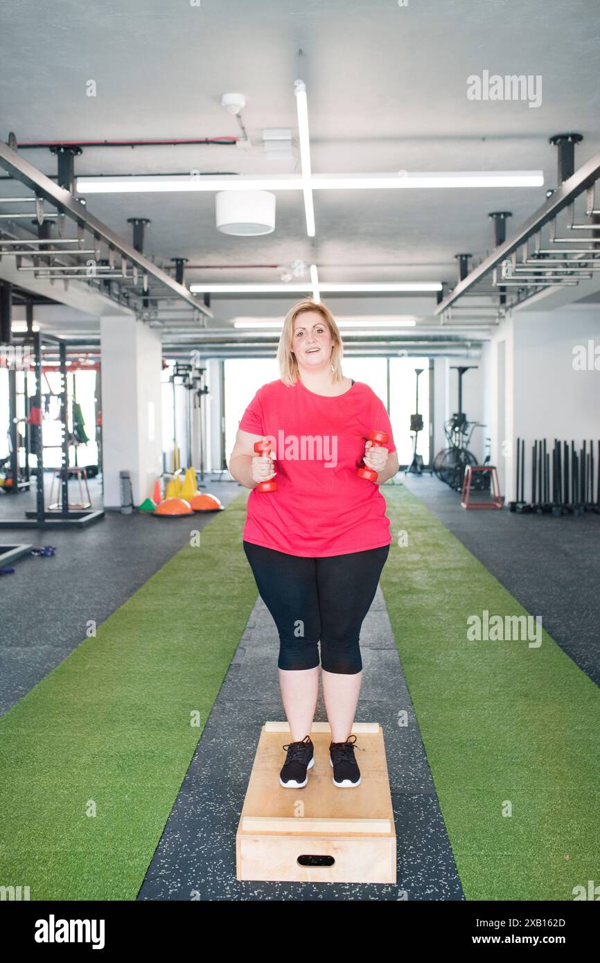 Overweight woman exercising in gym, using dumbbells Stock Photo - Alamy
