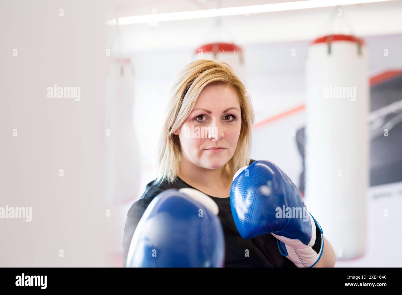 Overweight woman is working out in gym, boxing as part of her cardio ...