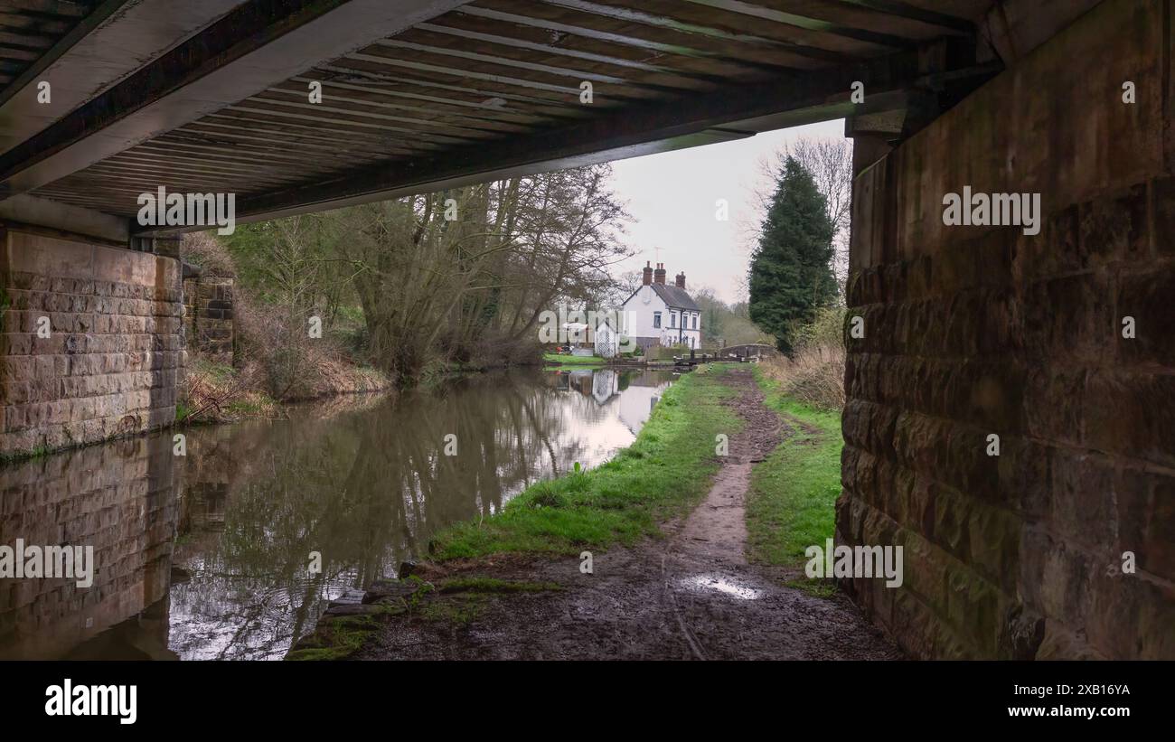 Standing on the towpath looking down the canal at a white lock keepers ...