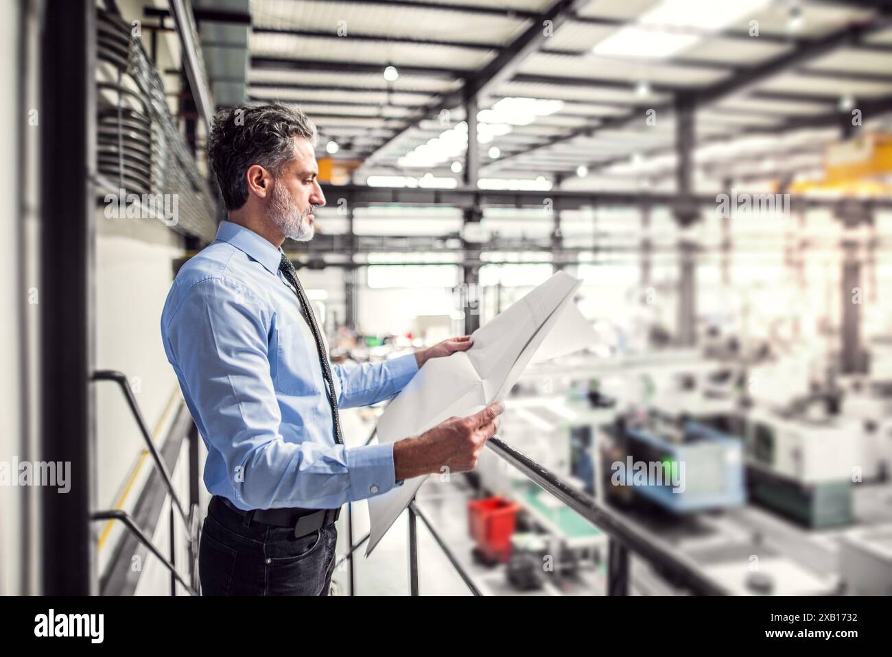 Portrait of project manager reading blueprint modern industrial factory ...