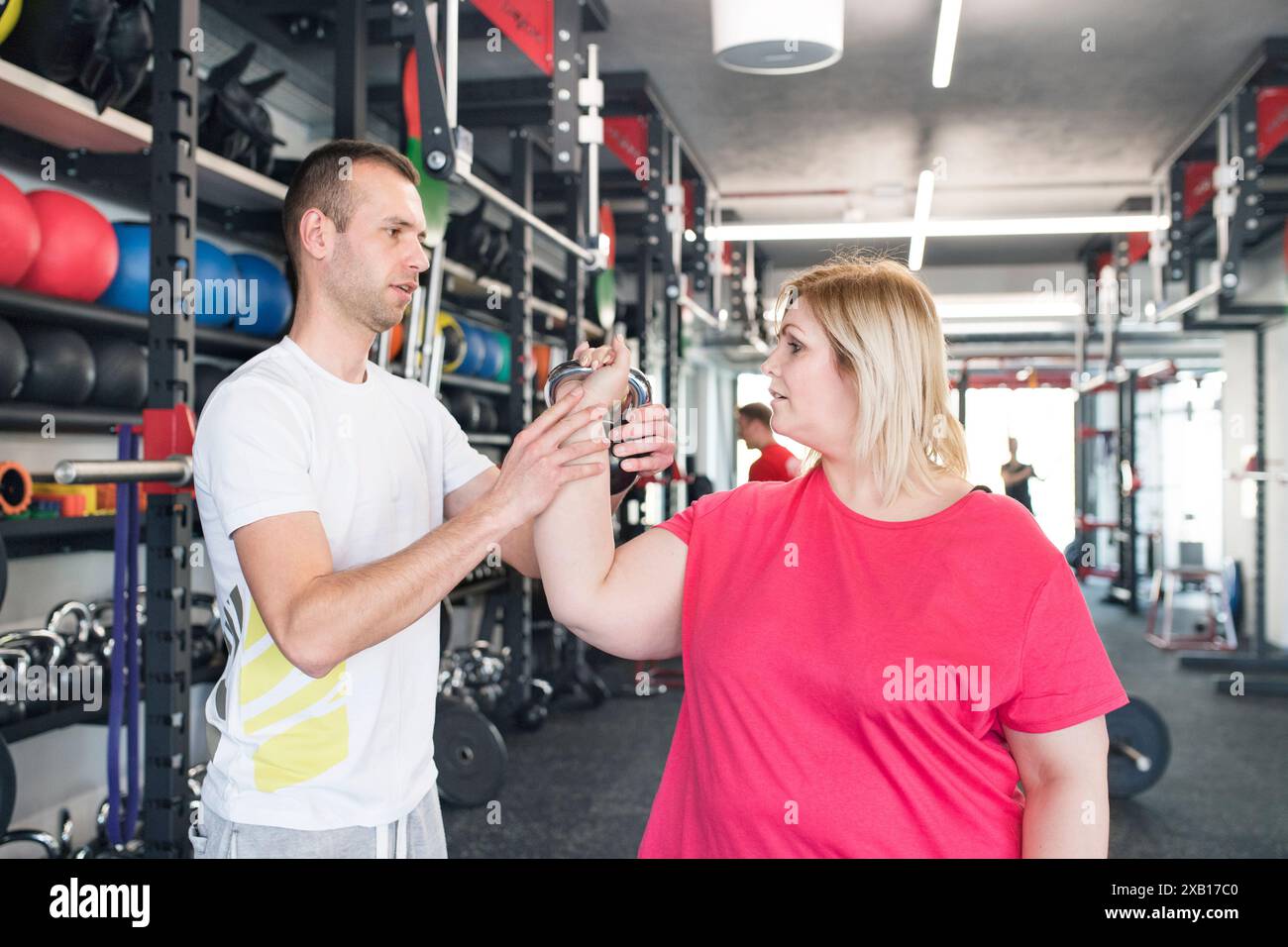 Overweight woman exercising in gym, using kettlebell. Personal trainer ...