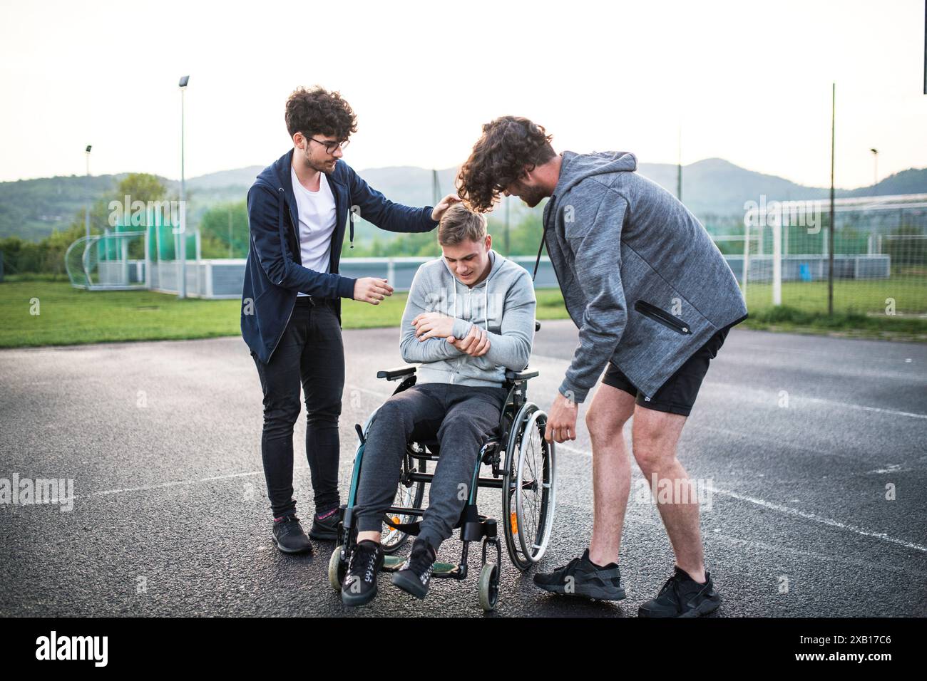 Young disabled man fall off wheelchair, fiends helping to sit back ...