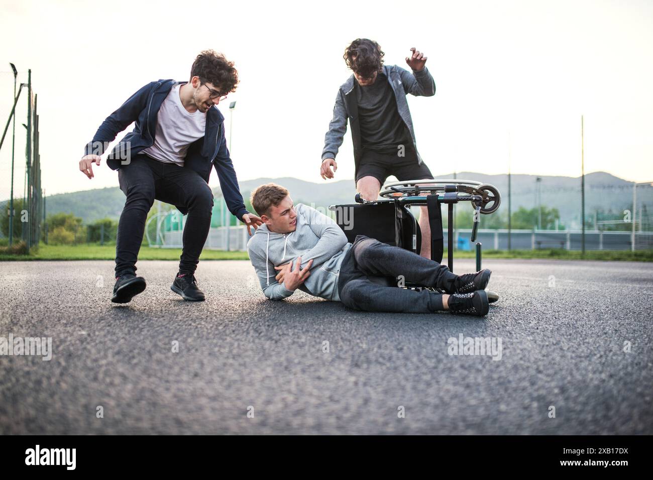 Young disabled man fall off wheelchair, fiends helping to sit back ...