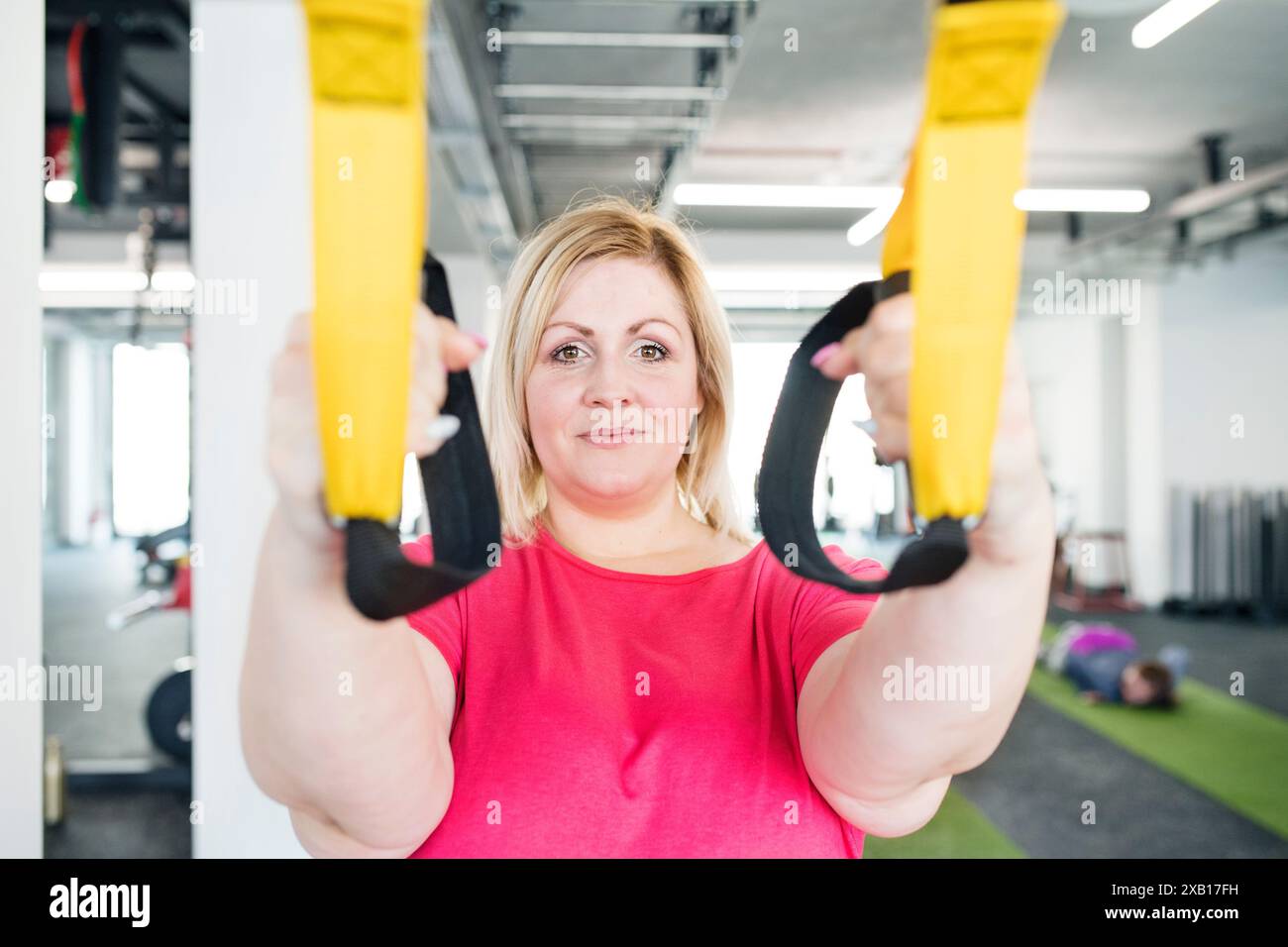 Overweight woman exercising in gym, doing suspension training, total ...