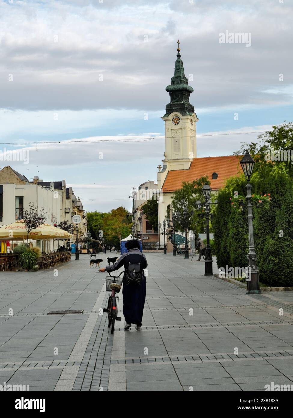 woman walking with bicycle along pedestrian street in Sombor, Serbia ...