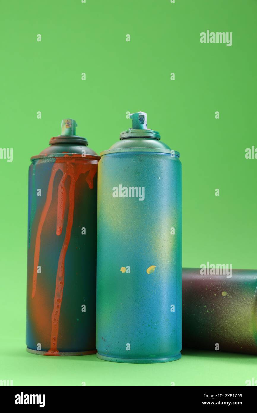 Bright spray paint cans on green background Stock Photo - Alamy