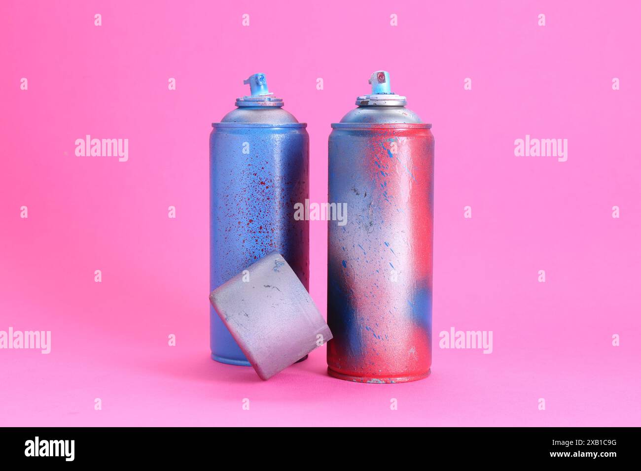 Spray paint cans with cap on pink background Stock Photo - Alamy