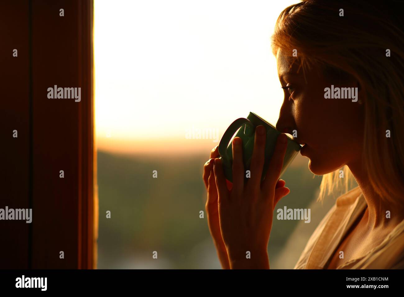 Profile of a thoughtful woman drinking coffee looking away through a ...