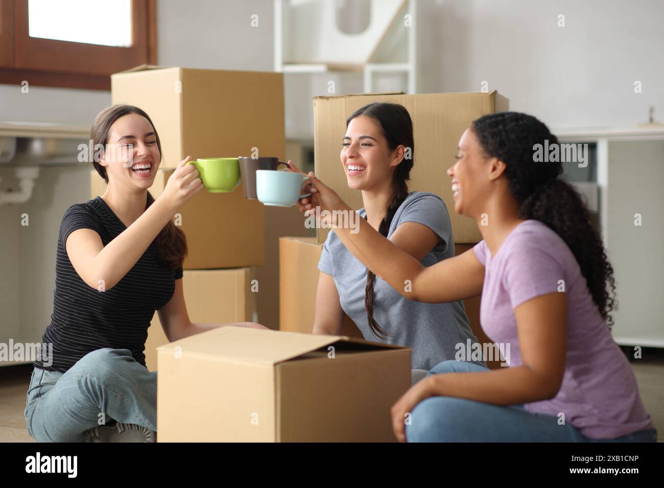 Three happy roommates toasting and celebrating moving house Stock Photo ...