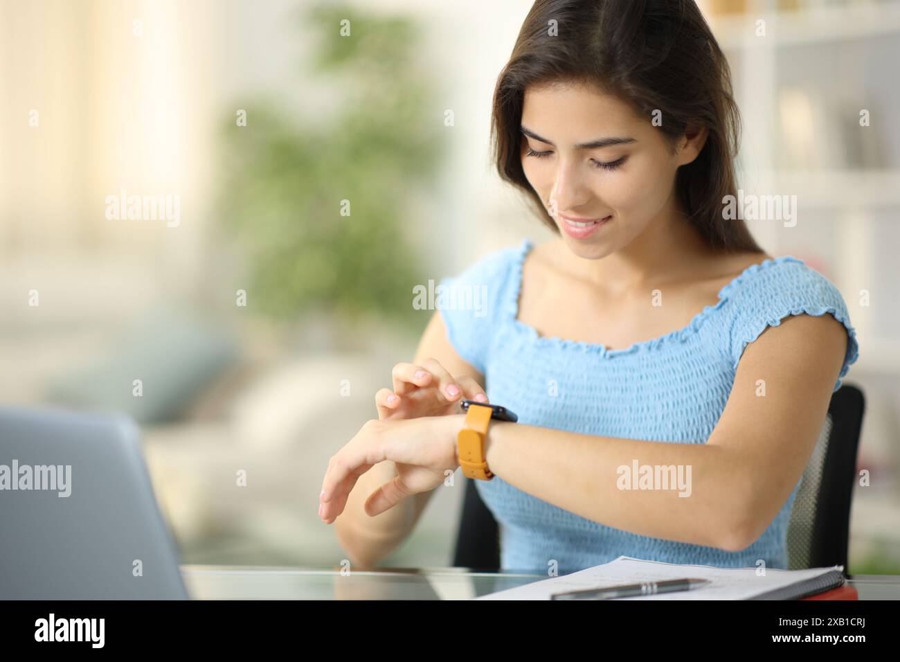 Happy student checking smartwatch sitting in a house interior Stock ...