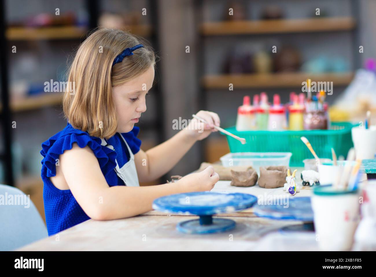 Child working on pottery wheel. Kids arts and crafts class in workshop ...