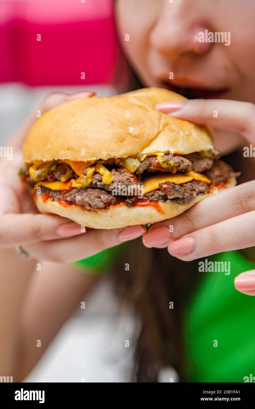 Closeup of a female having double smashed beef donut burger in a cafe ...