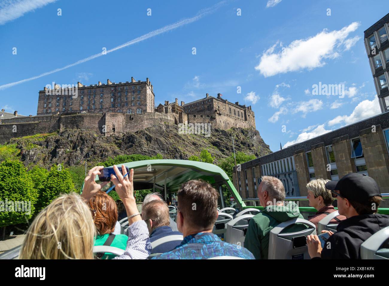 Group of tourists enjoying open top bus tour of Edinburgh, passing ...