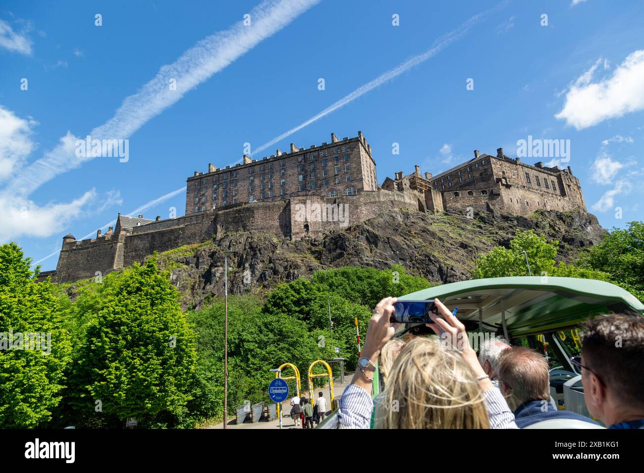 Group of tourists enjoying open top bus tour of Edinburgh, passing ...