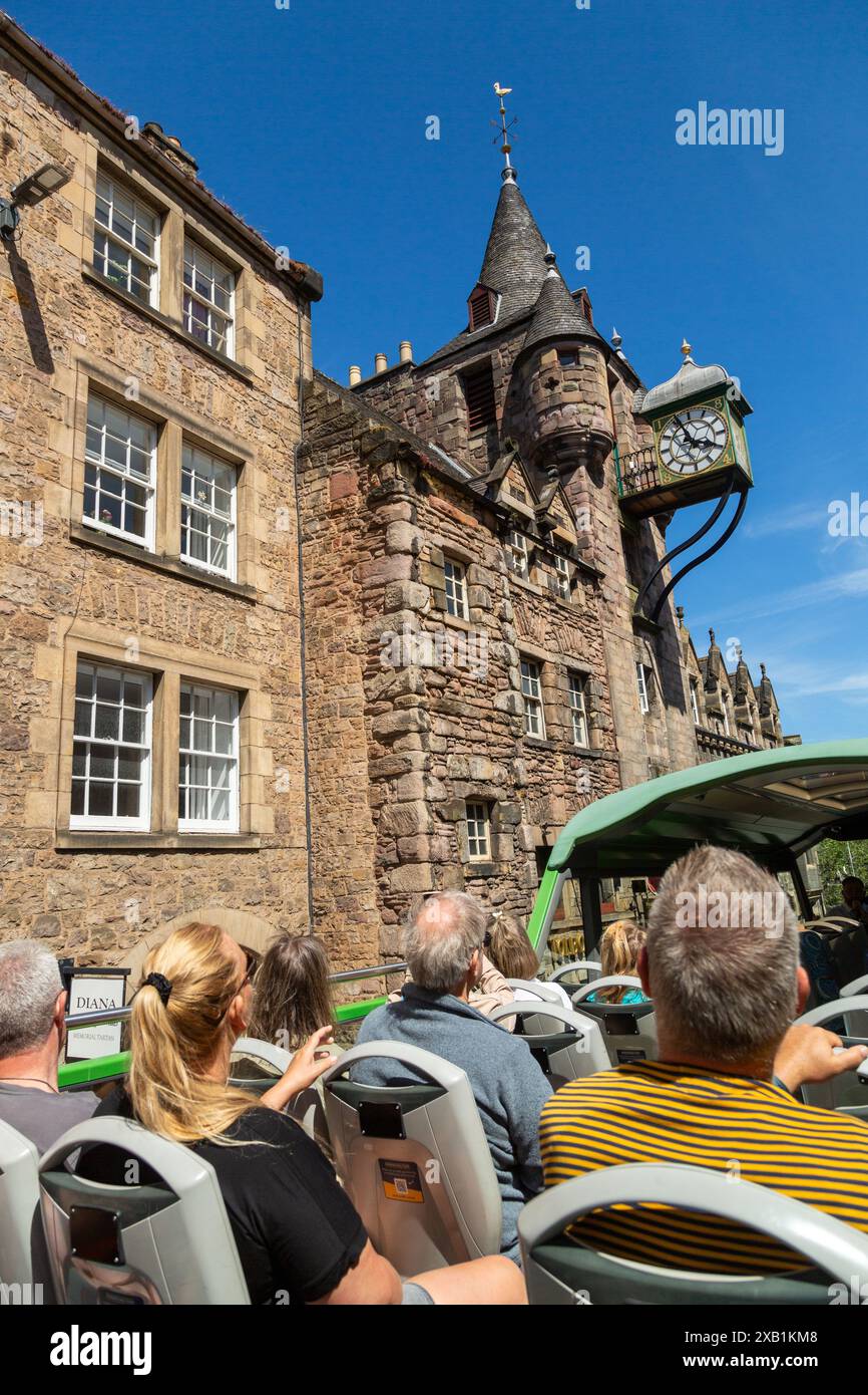 Group of tourists enjoying open top bus tour of Edinburgh, passing ...