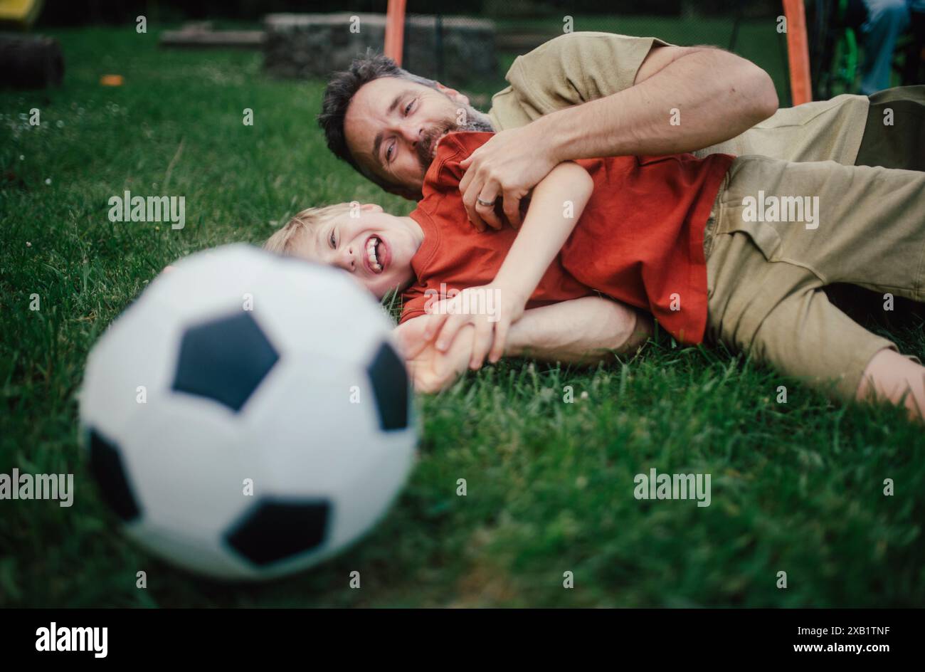 Dad lying on grass with son, laughing and having fun. Father and boy ...