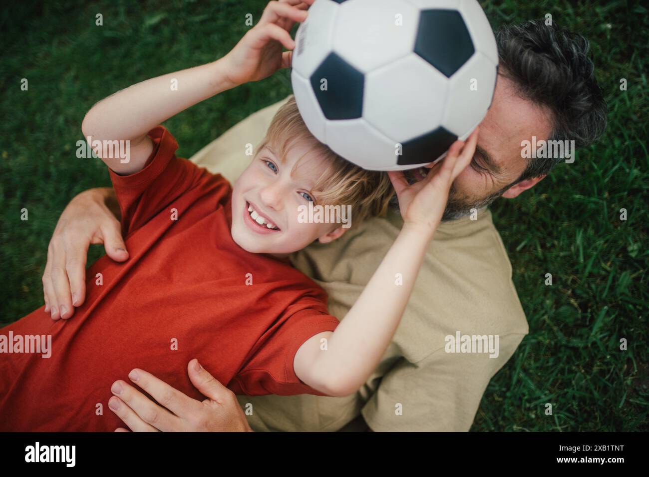 Dad lying on grass with son, laughing and having fun. Father and boy ...
