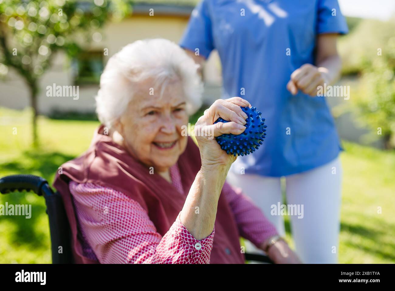Female caregiver doing motorized exercises with senior woman in ...