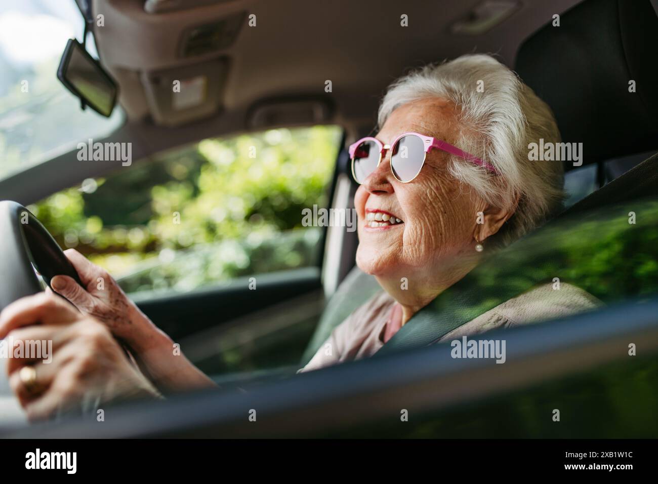 Happy senior woman driving car alone, enjoying car ride. Safe driving ...