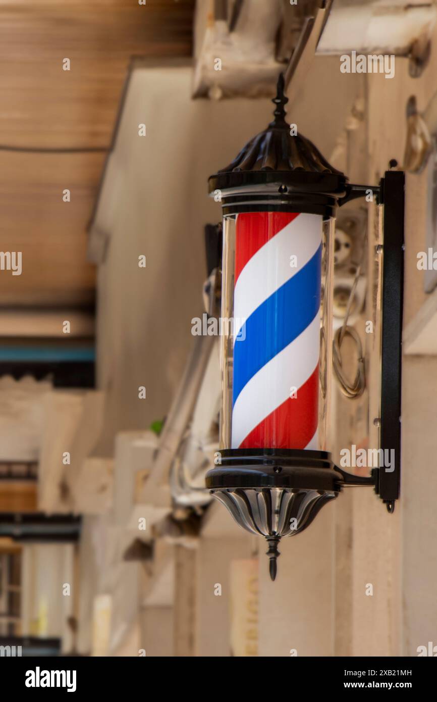 A classic barber pole sign with red, white, and blue stripes outside a ...