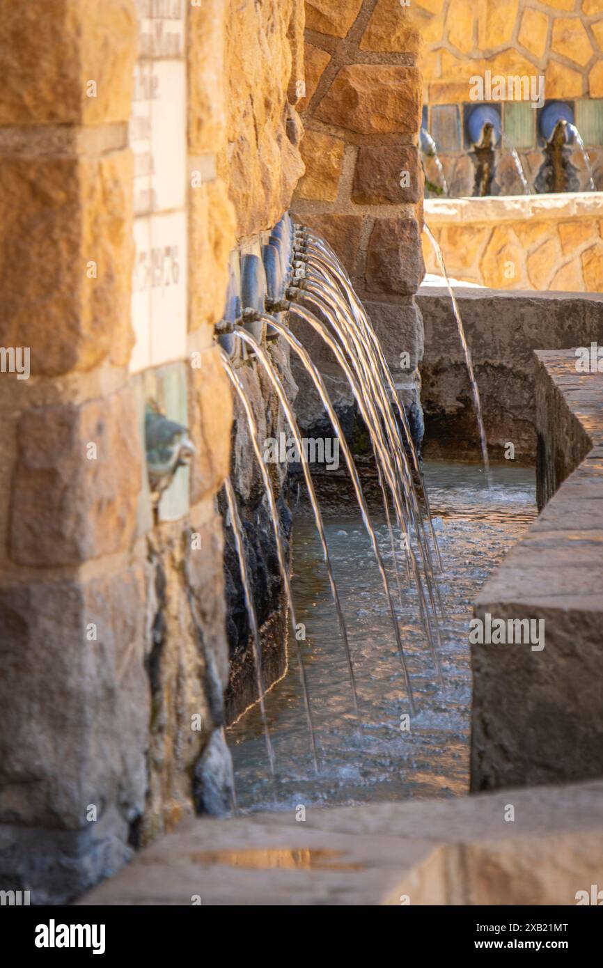 A rustic stone water fountain featuring multiple streams of flowing ...