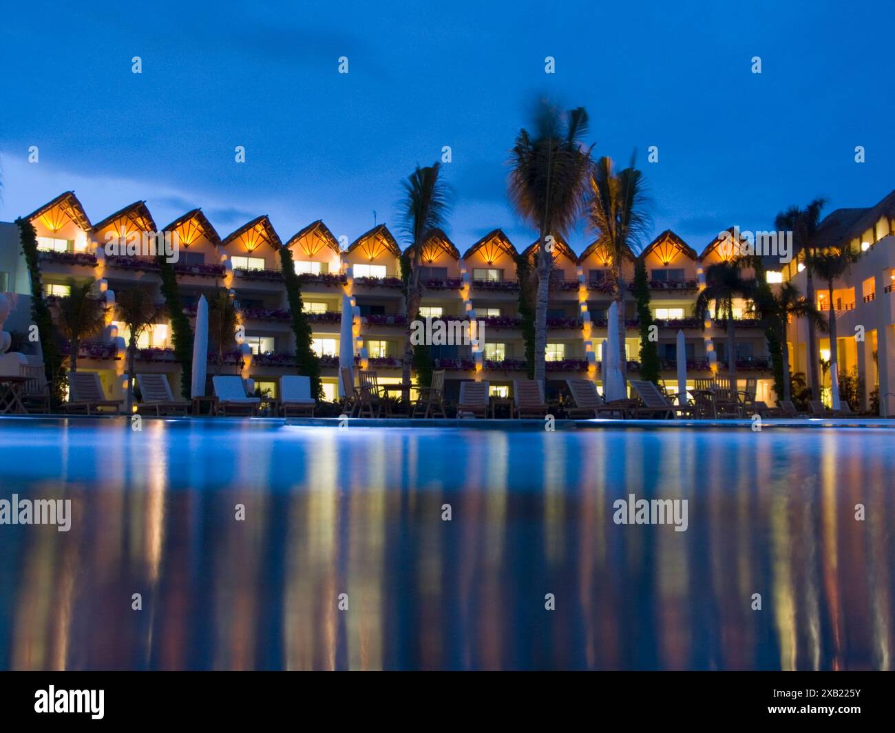 Lights of hotel rooms reflected in pool at a resort hotel Stock Photo ...