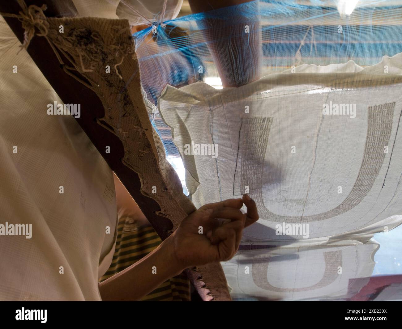 A worker stitches fabric in the Mumbai, India workshop/office of an ...