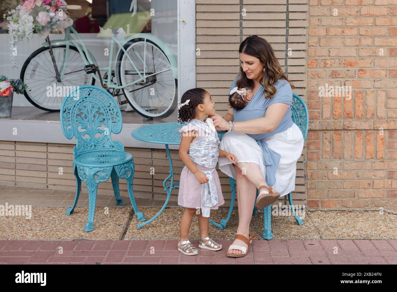mom and daughter sit together outside while shopping downtown Stock ...